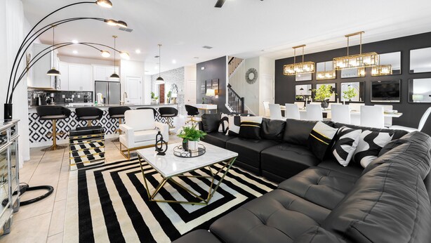 Uma sala de estar moderna com um tapete listrado em preto e branco, um sofá preto e uma mesa de centro branca.