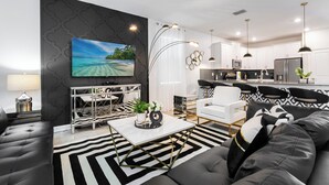 Uma sala de estar moderna com um tapete listrado em preto e branco, um sofá, uma mesa de centro e uma TV fixada na parede.