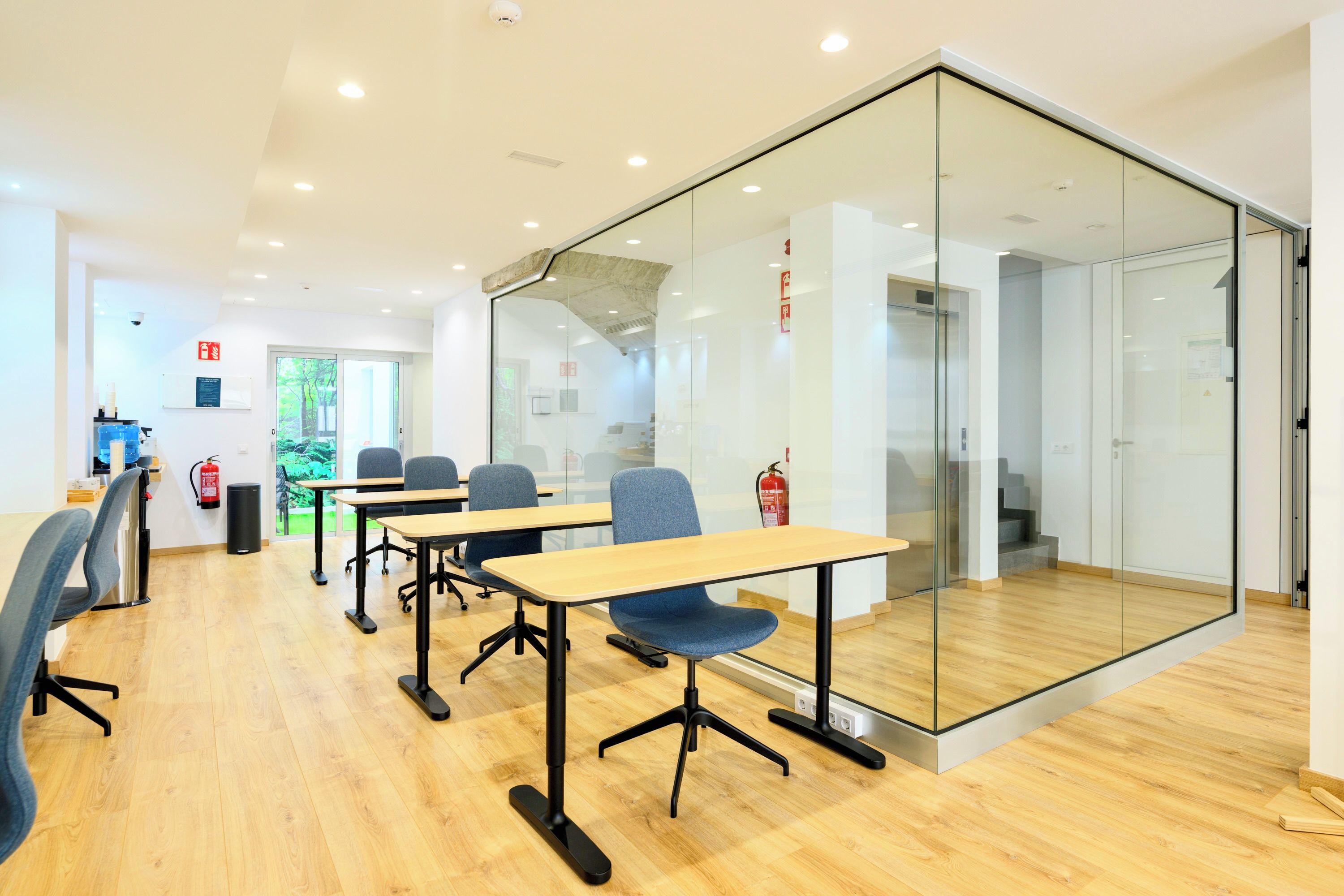 Sala de conferências moderna com paredes de vidro, piso de madeira e cadeiras ergonômicas.