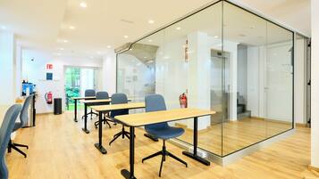 Sala de conferências moderna com paredes de vidro, piso de madeira e cadeiras ergonômicas.
