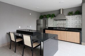 Cozinha moderna com ilha central, forno embutido e frigorífico em aço inoxidável.