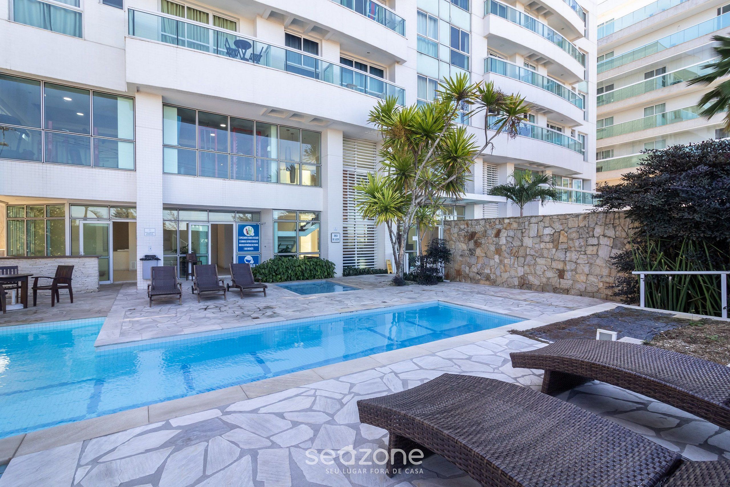 Um hotel moderno com piscina, área de estar externa e uma parede de pedra.