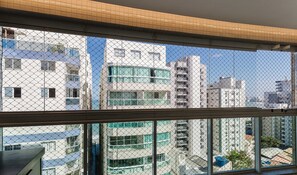 Visão através de uma cerca de arame de edifícios modernos altos, com várias varandas e janelas amplas.