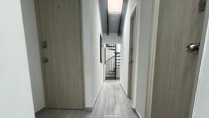 Um corredor com piso de madeira, paredes brancas e uma escada no final.