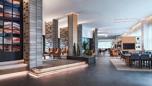 Um lobby de hotel moderno com área de estar central, tetos altos e uma grande janela.