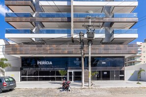 Um edifício moderno com várias varandas e uma fachada de vidro extensa.