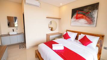 Quarto de hotel com cama, mesa de cabeceira, espelho, ar condicionado fixado na parede e um quadro.