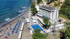 Um hotel à beira-mar com piscina, guarda-sóis e vista para o mar.