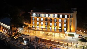 Um hotel com piscina, várias varandas e fachada bem iluminada.
