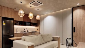 Cozinha moderna com sofá embutido, luminárias pendentes e área de jantar com cadeira preta.