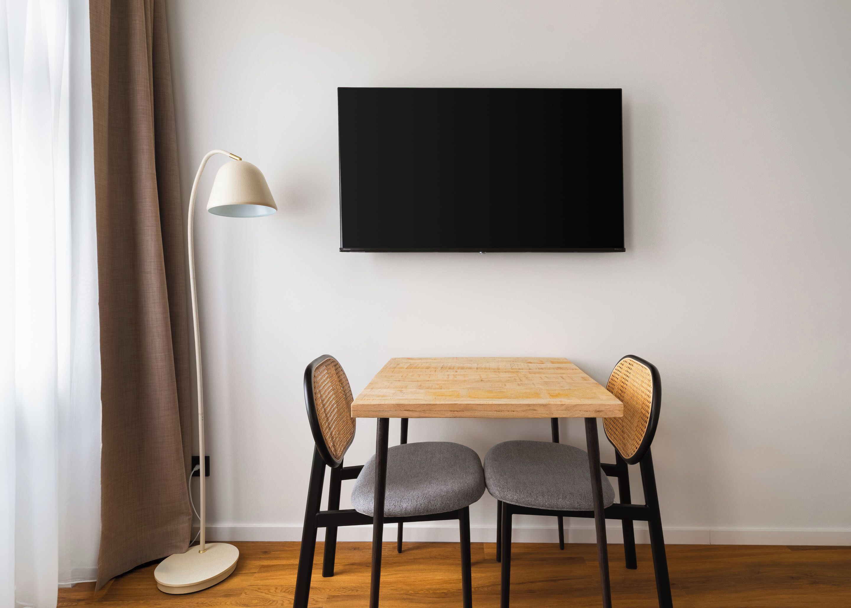 Uma sala de jantar com uma mesa de madeira e quatro cadeiras, um abajur e um quadro com moldura preta na parede.