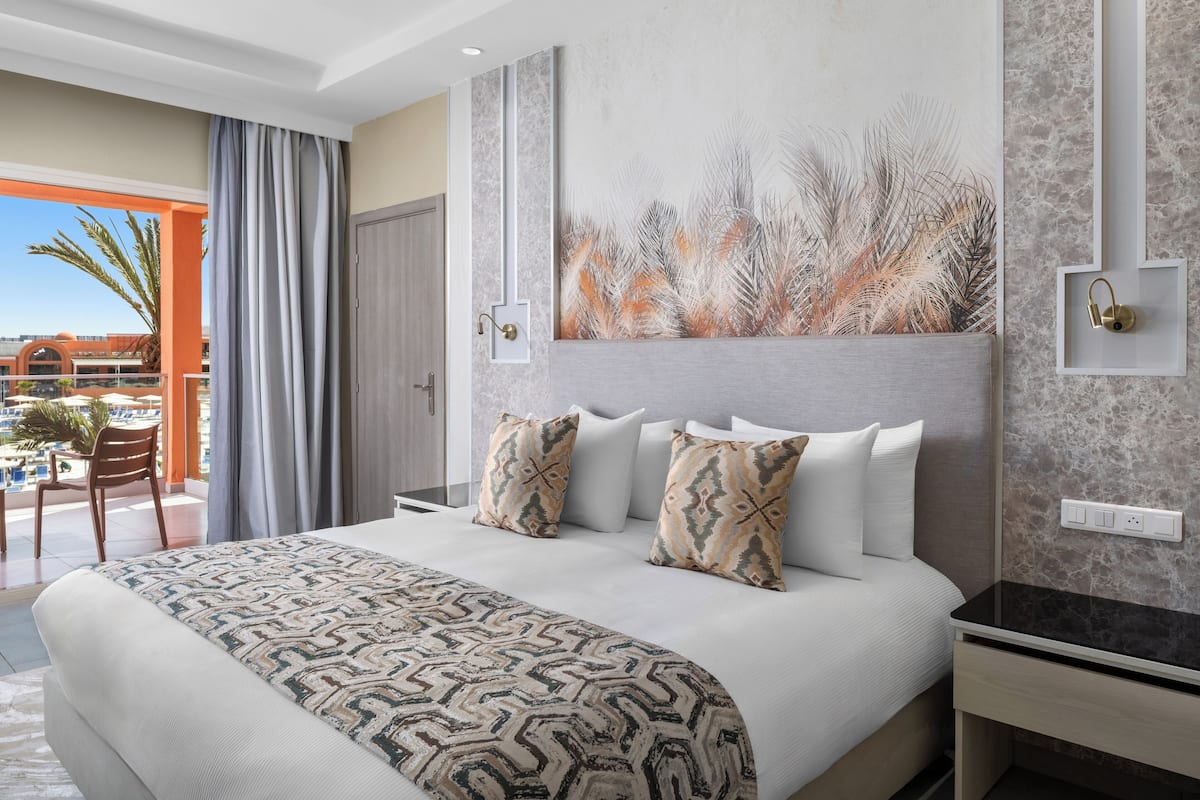 Quarto de hotel com uma cama grande, vista para a piscina e design moderno.