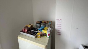 Uma cozinha compacta equipada com cafeteira, chá, cereais e lanches.