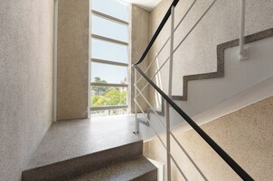 Escada com corrimão de metal, janela e vista para o verde lá fora.