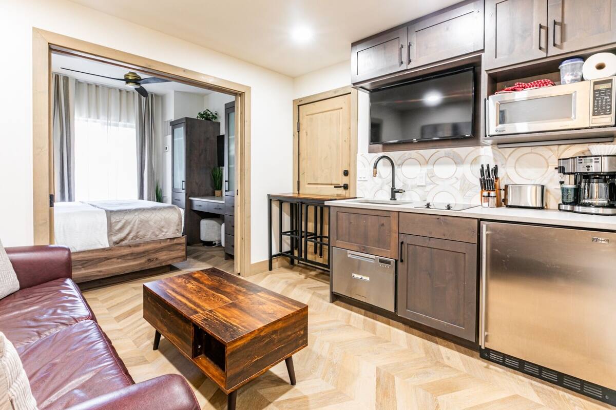 Um espaço compacto com cozinha compacta, cama, área de refeições e um pequeno espaço para sentar.