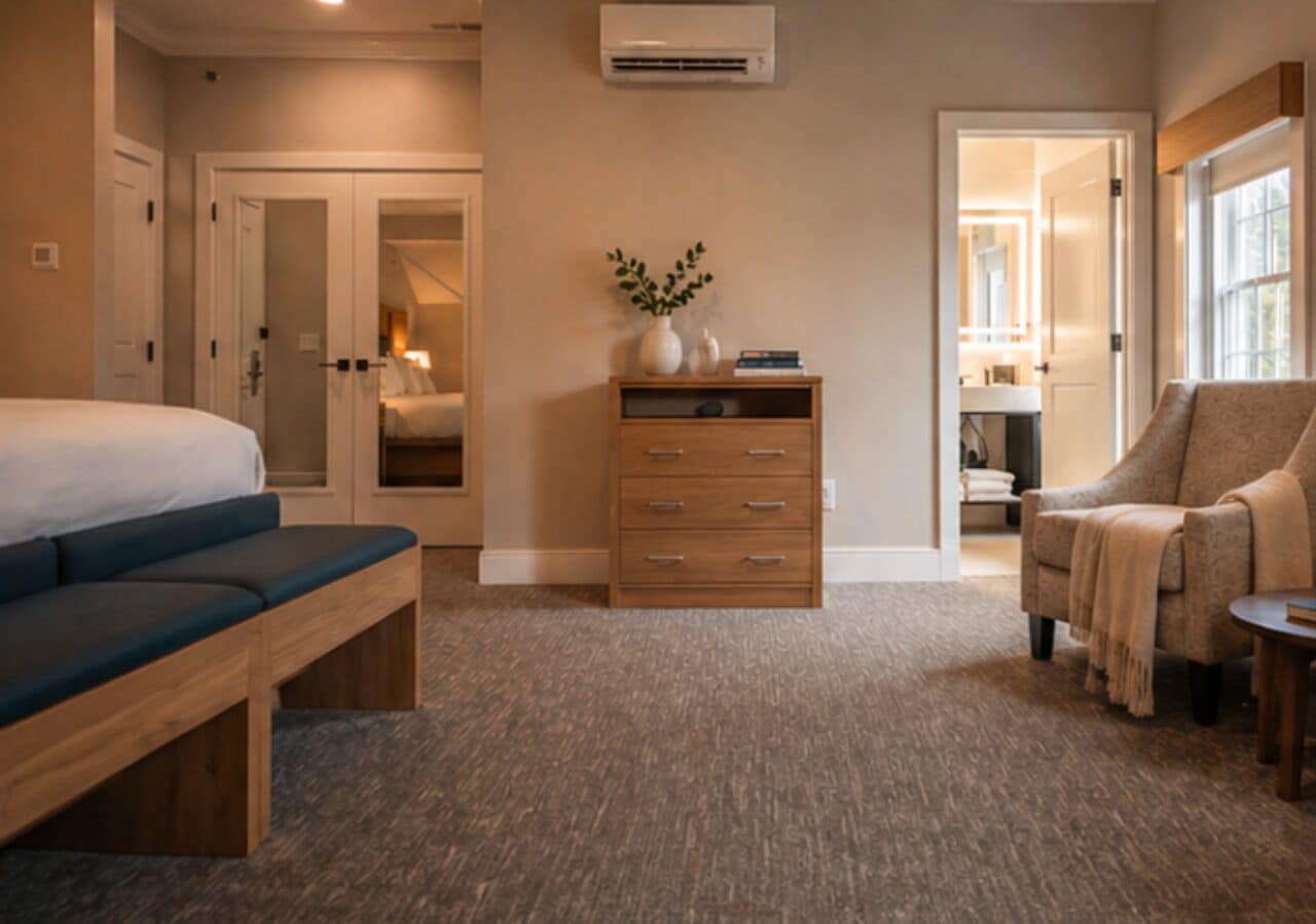 Um quarto com uma cama, um banco, uma cômoda e uma cadeira.