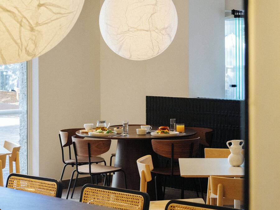 Um restaurante com mesa redonda, cadeiras e luminárias pendentes.