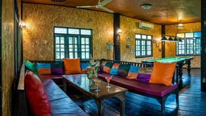 Um quarto acolhedor com mesa de bilhar, paredes de madeira e assentos coloridos.