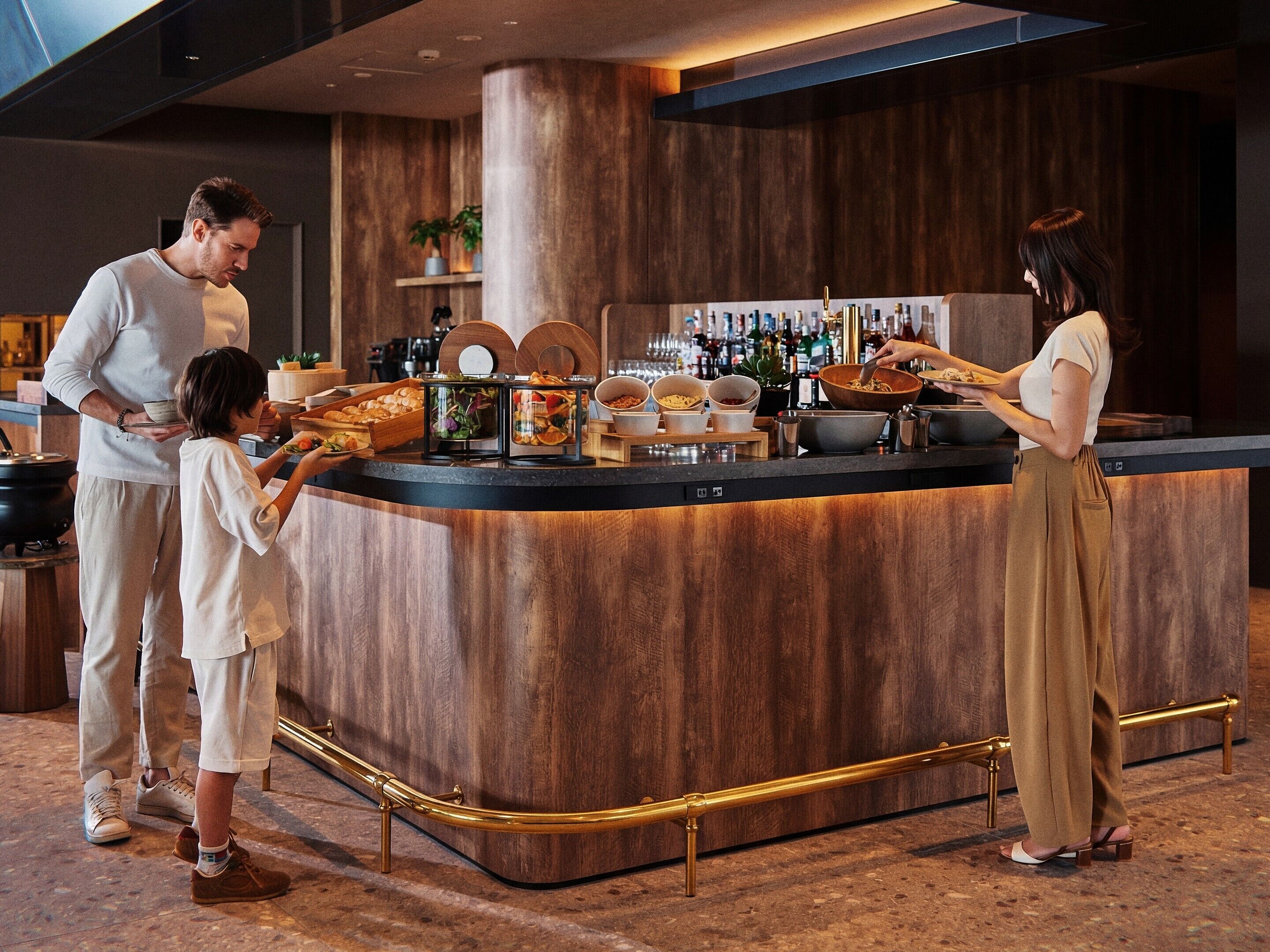 Uma área de bar moderna com balcão de madeira, diversos recipientes de comida e bebida, e um bar abastecido com garrafas.