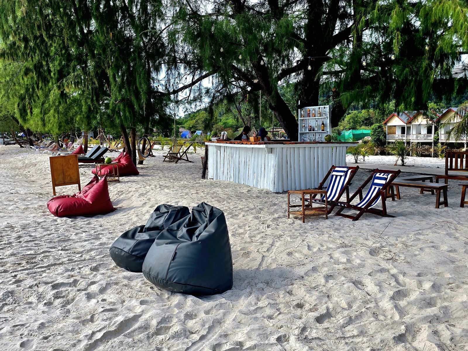 Uma área de relaxamento à beira-mar, com espreguiçadeiras, pufes e um bar.