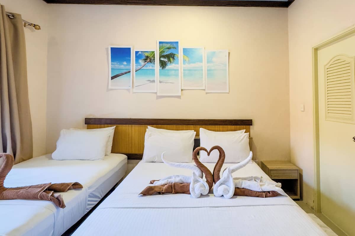 Quarto de hotel com duas camas, cabeceira de madeira e luminária no teto.