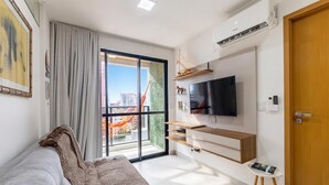 Quarto moderno com uma janela grande, televisão de tela plana e porta deslizante para uma varanda.