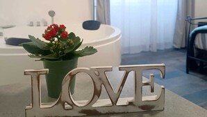 Quarto com uma janela grande, uma banheira e uma placa com a palavra 'LOVE'.