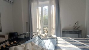 Quarto de hotel com cama, escrivaninha e janela com cortinas.