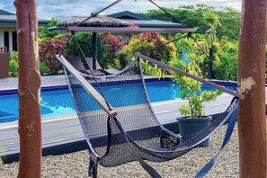 Uma cadeira rede junto a uma piscina, com uma estrutura de telhado de palha e uma placa para o Seatiki Resort Fiji.
