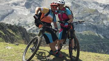Duas pessoas em uma montanha com bicicletas, em meio a terreno rochoso e vegetação.