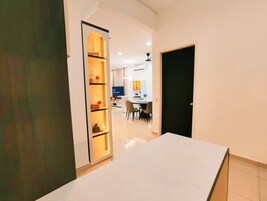 Interior moderno com uma mesa branca, área de cozinha e espaço para refeições.