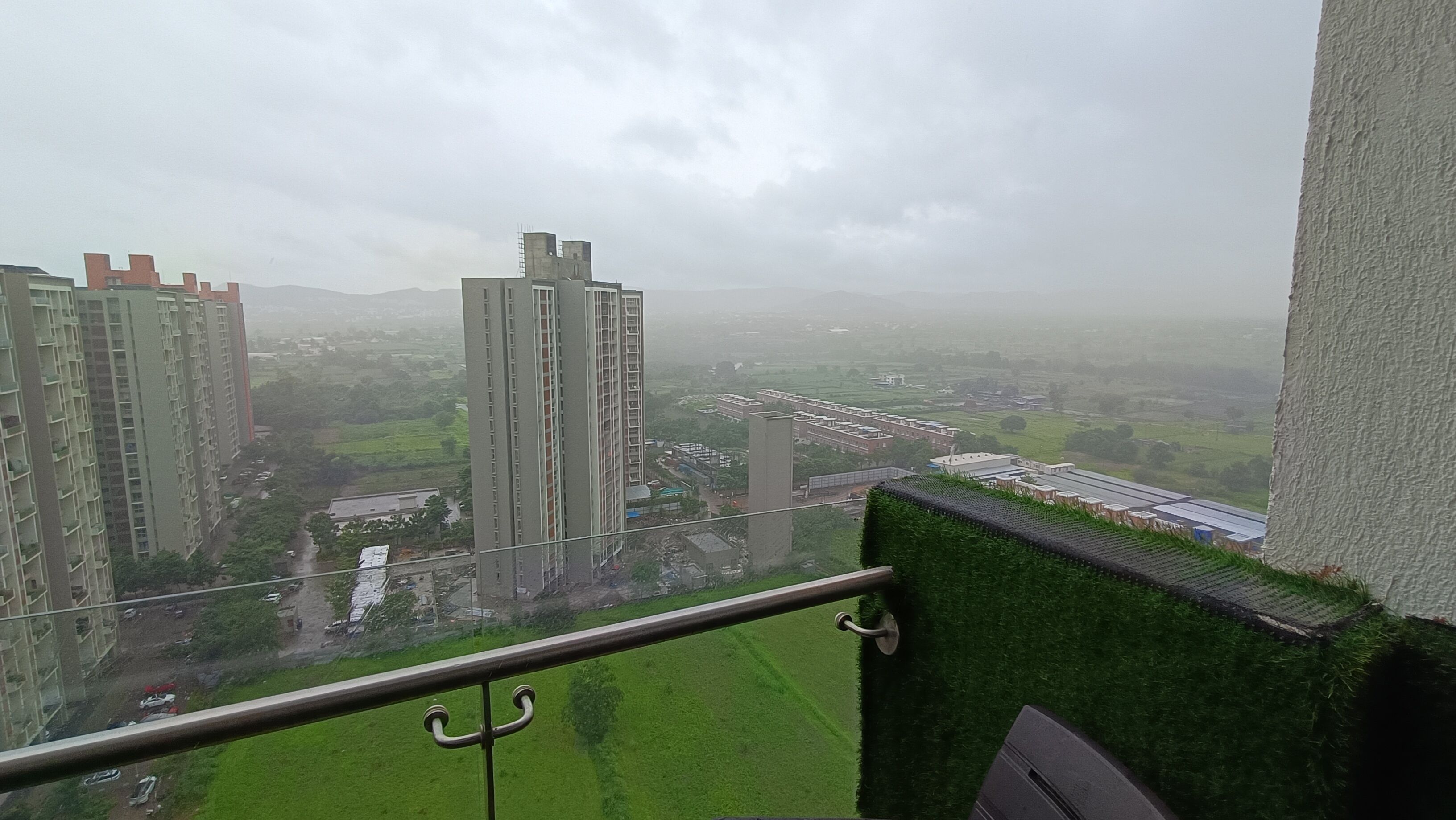 Um edifício alto com vários andares e varandas, com vista para uma paisagem verde com campos e outros edifícios.