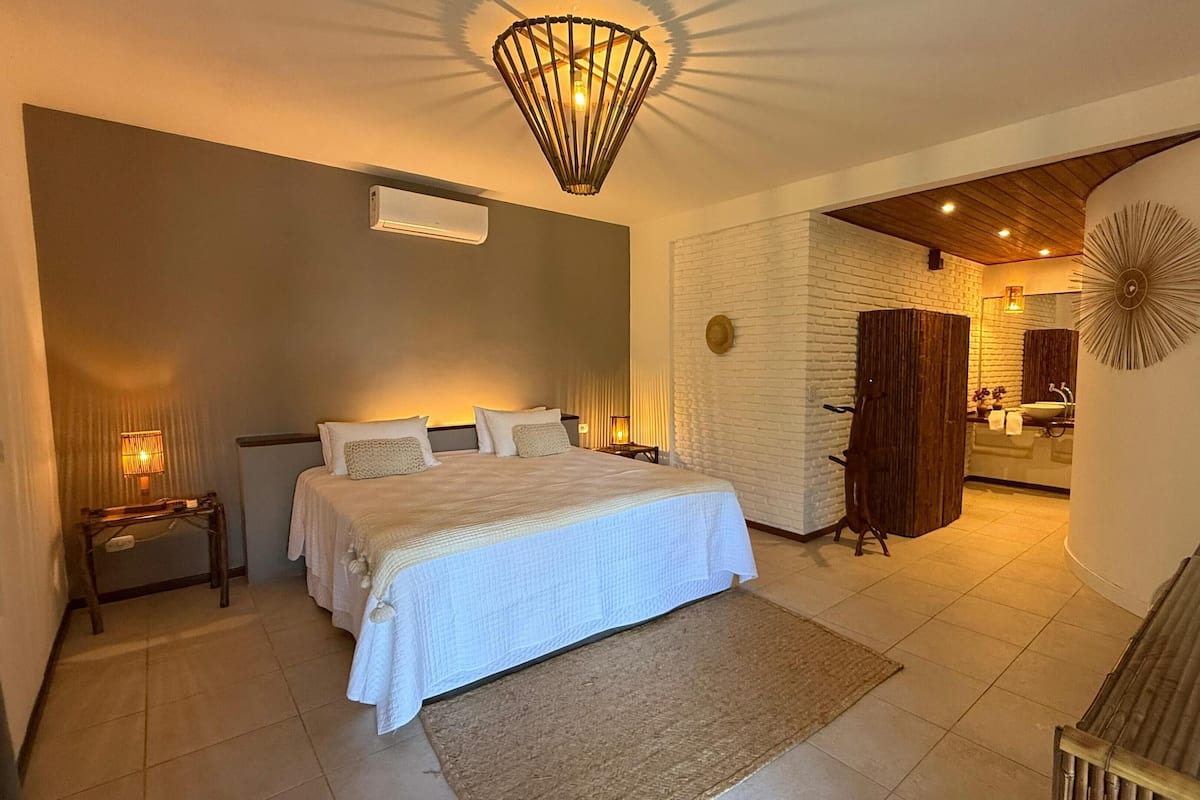Quarto espaçoso com uma cama grande, mesa de cabeceira, abajur e luminária no teto.
