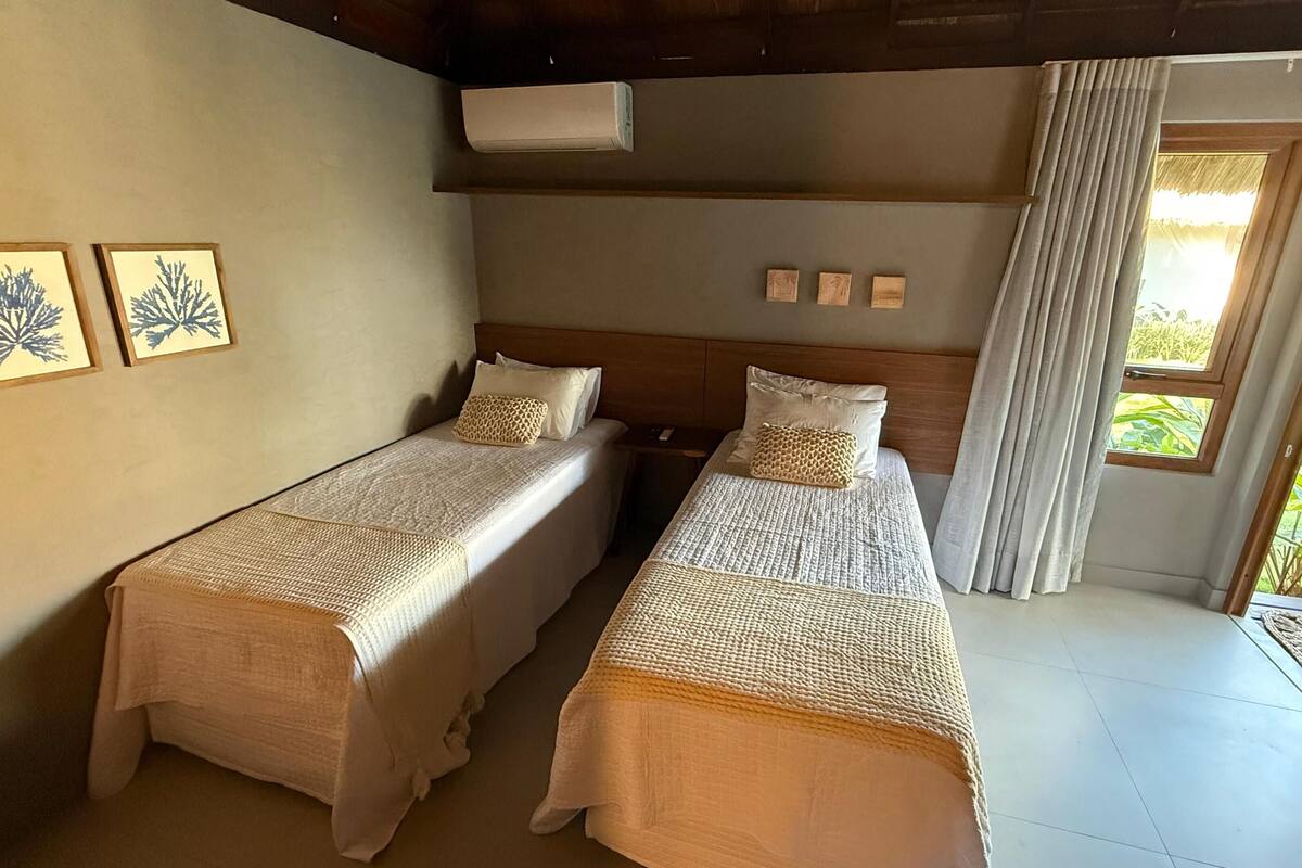 Quarto com duas camas, um ventilador de teto e uma janela com cortinas.