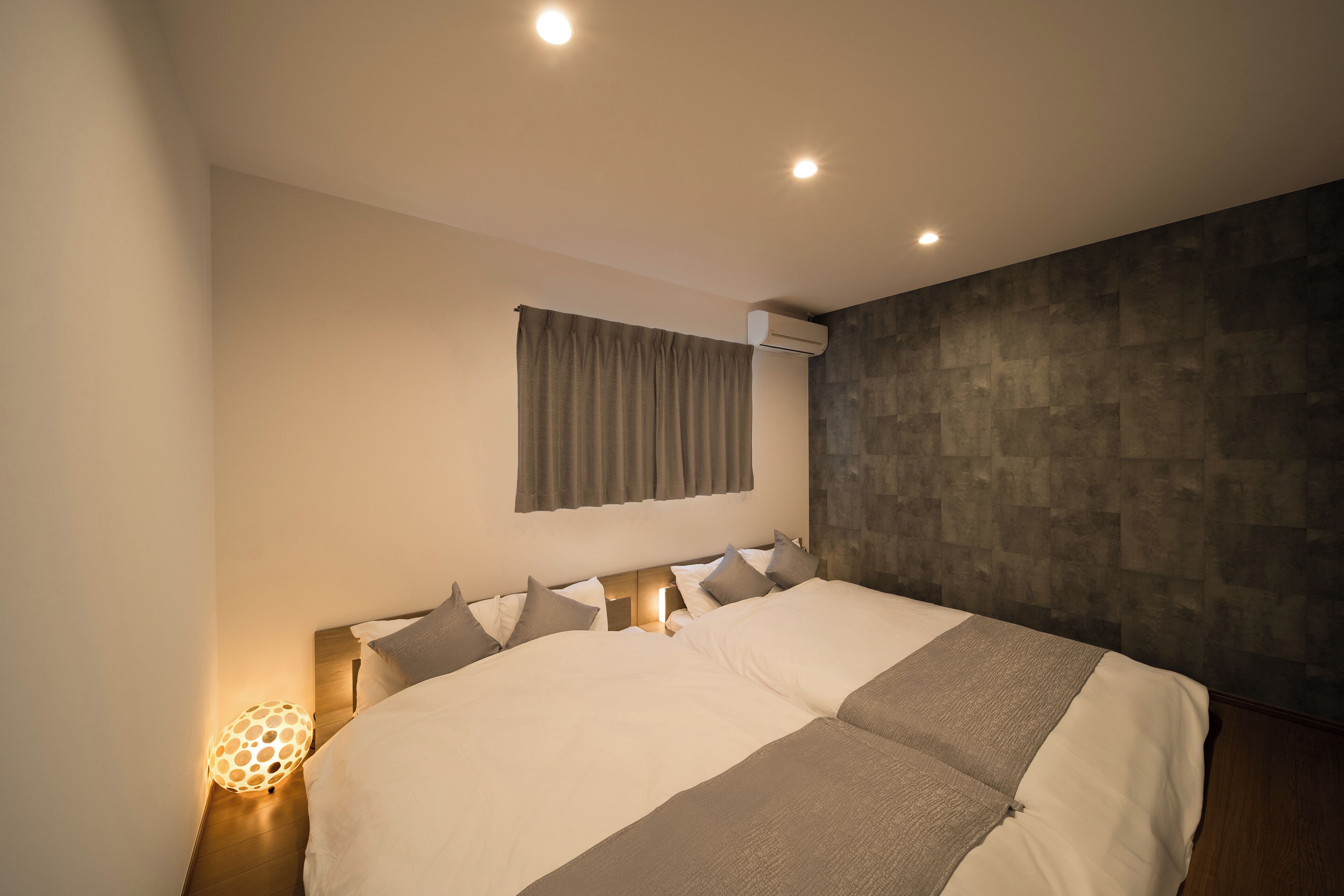 Quarto moderno com uma cama grande, luminária de cabeceira e ar-condicionado fixado na parede.