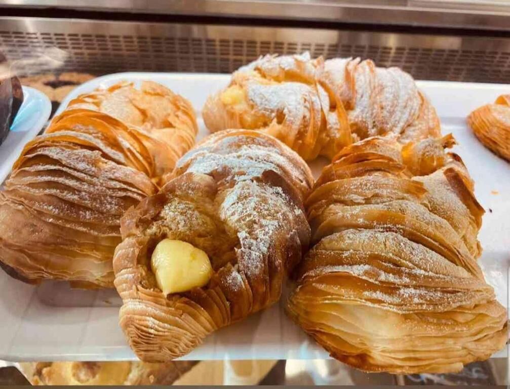Exposição de doces, incluindo croissants e um doce com recheio.
