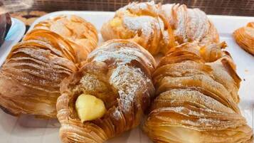 Exposição de doces, incluindo croissants e um doce com recheio.