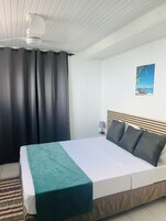 Quarto com cama, cortinas, um quadro e um ventilador de teto.