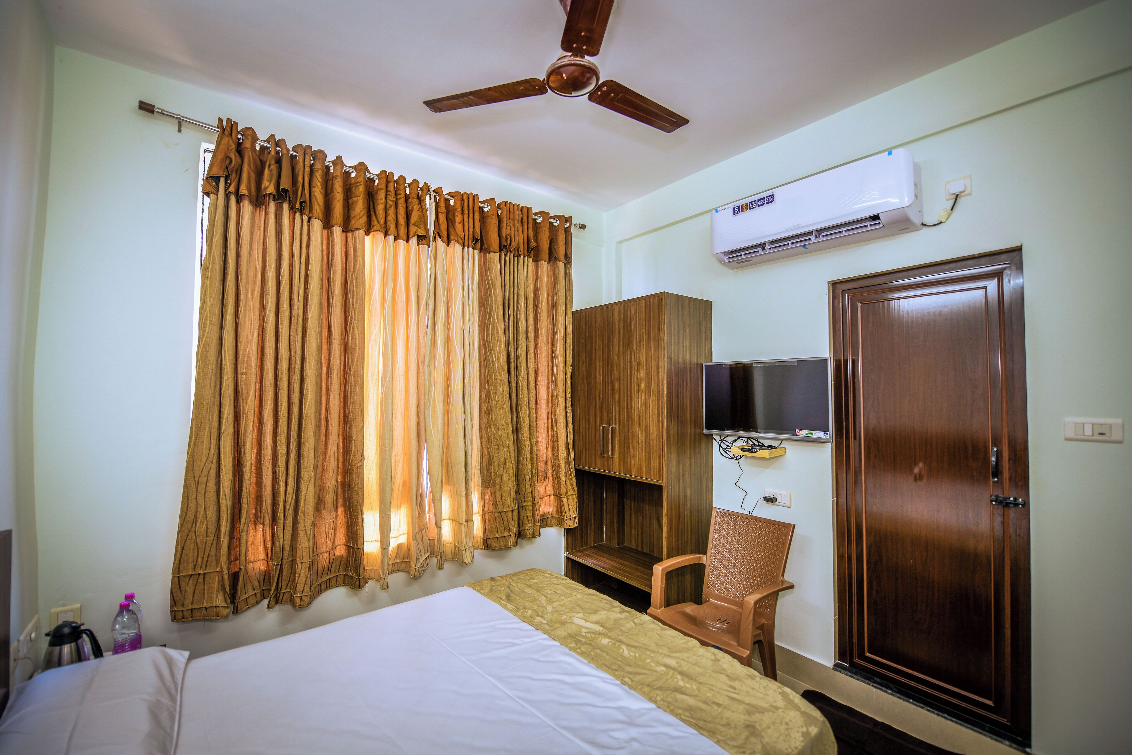 Quarto de hotel com cama, guarda-roupa de madeira, televisão e ar condicionado.