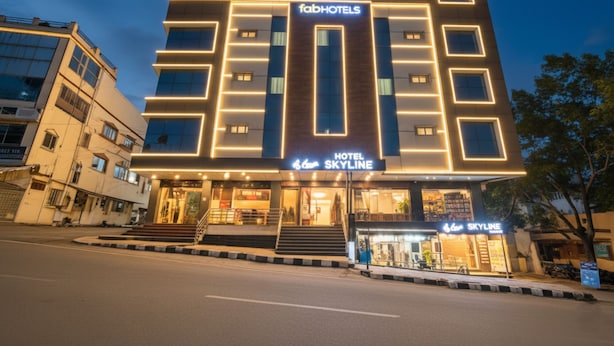 Um edifício de hotel moderno com uma placa chamativa 'fabHOTELS', uma placa 'HOTEL SKYLINE' e uma entrada visível com degraus que levam à porta.