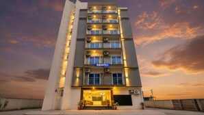 Um hotel com vários andares, fachada moderna, varandas e uma placa indicando ser uma propriedade FabHotels.