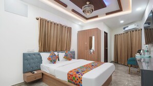 Quarto moderno com cama grande, guarda-roupa de madeira, escrivaninha com cadeira e um candelabro.