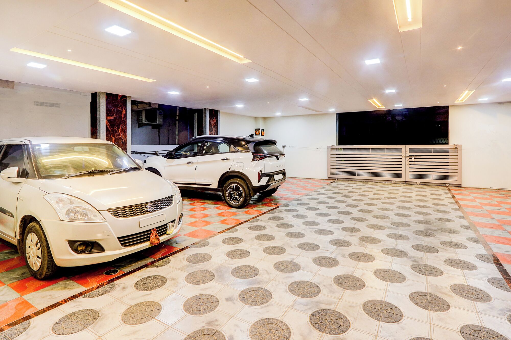 Um parque de estacionamento com dois carros estacionados, soalho em azulejo e sistema de ventilação.