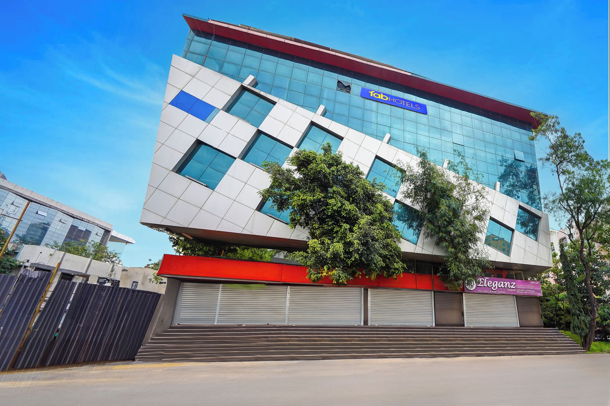 Um edifício moderno com uma placa 'fab hotel', janelas amplas e fachada vermelha e branca.