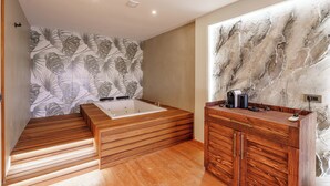 Uma casa de banho moderna com uma banheira de madeira, toucador com painel de mármore e papel de parede com padrão de folhas.