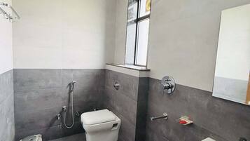 Casa de banho com sanita, lavatório e chuveiro.
