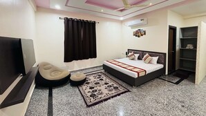 Quarto moderno com cama, TV de tela plana, ventilador de teto e piso coberto por carpete.