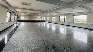 Interior espaçoso e bem iluminado, com piso lustroso, janelas amplas e design moderno no teto.