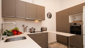 Uma cozinha moderna com bancada branca, eletrodomésticos de aço inoxidável e armários marrons.