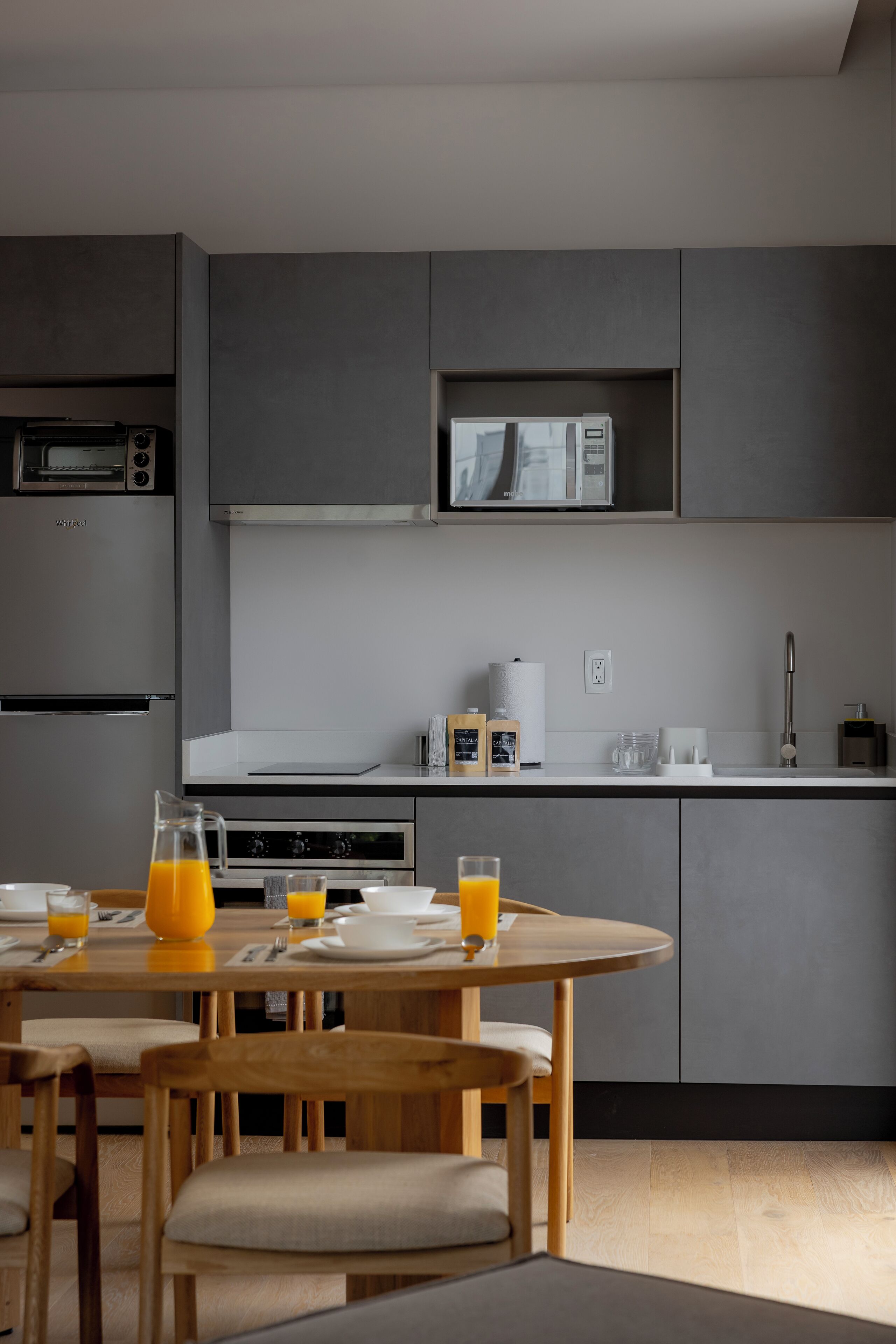 Cozinha moderna equipada com micro-ondas embutido, forno elétrico e geladeira de aço inoxidável.